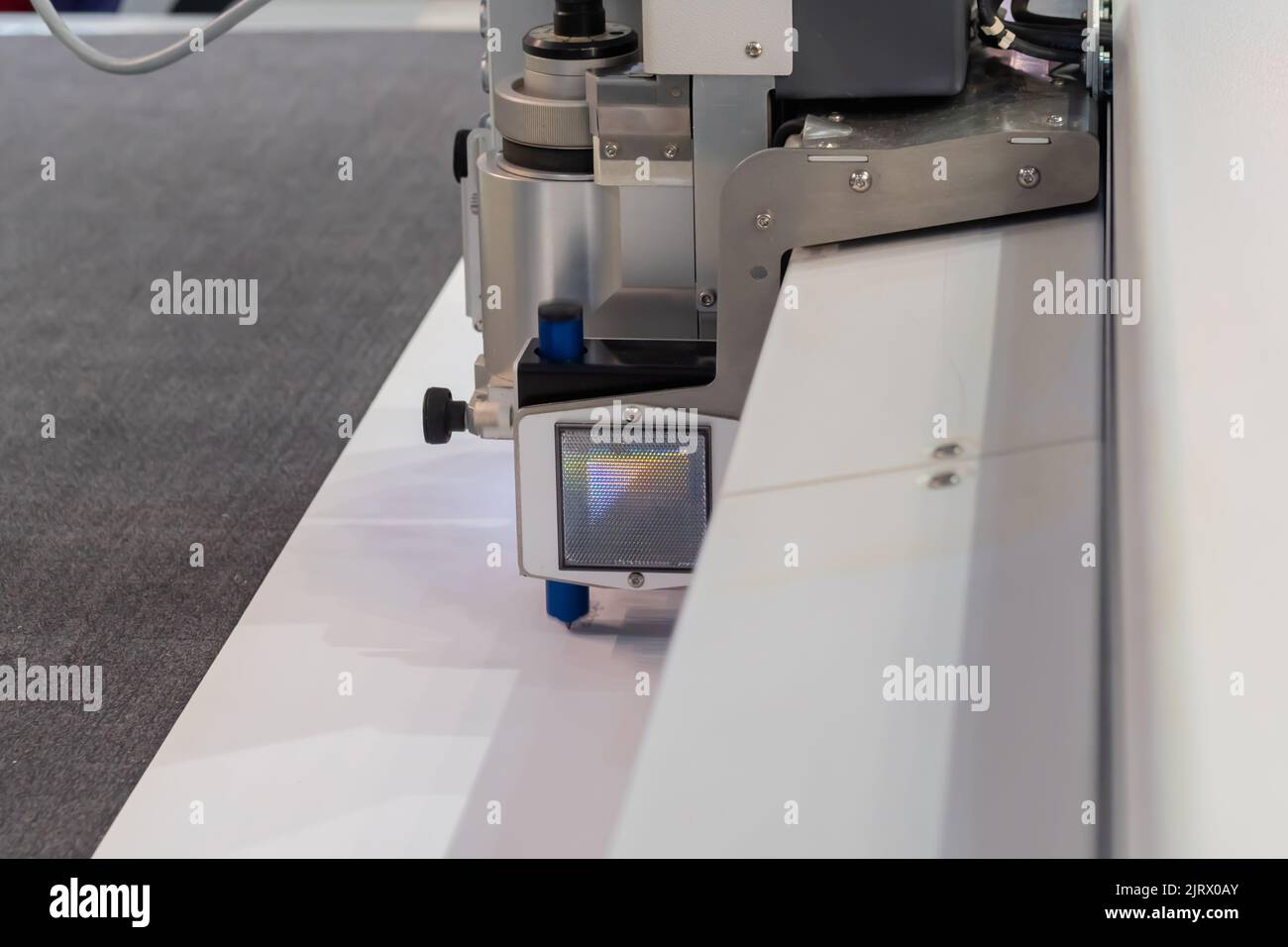 Flatbed cutter with drawing pen module writing text on white plastic ...