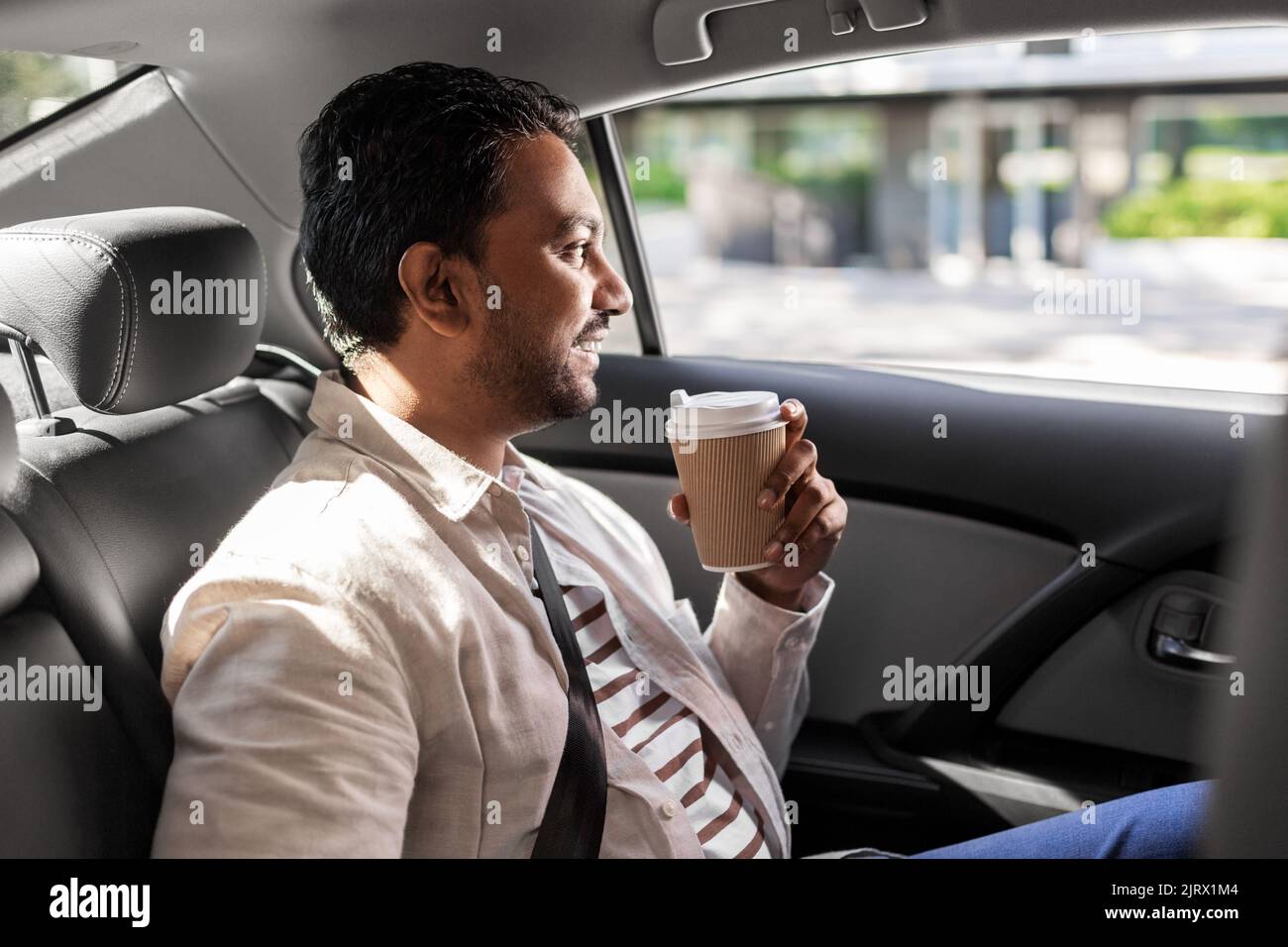indian man with takeaway coffee on car back seat Stock Photo - Alamy