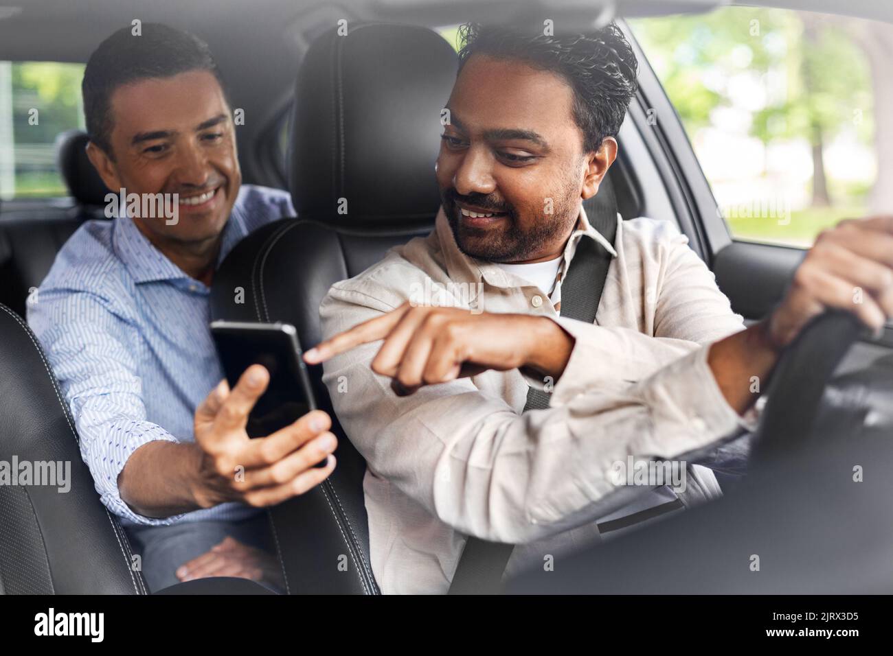 male passenger showing smartphone to car driver Stock Photo - Alamy