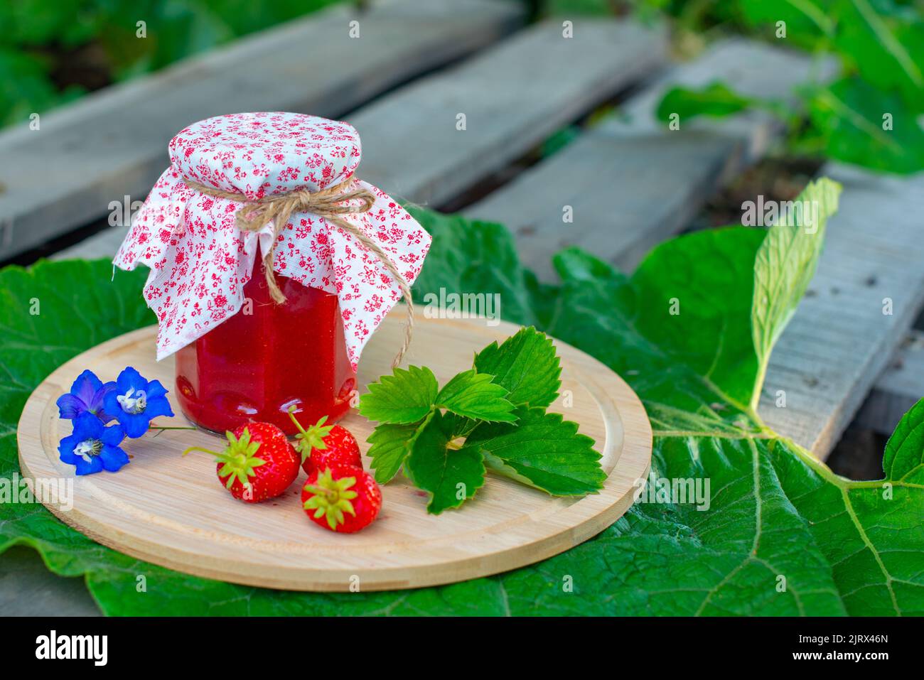a jar of strawberry jam stands on a board Stock Photo - Alamy