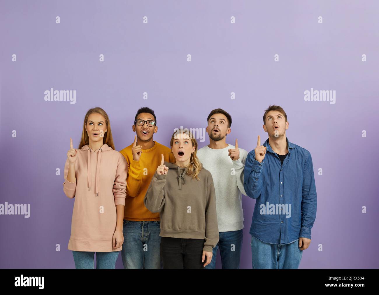 Multiracial young people look surprised pointing at something up ...