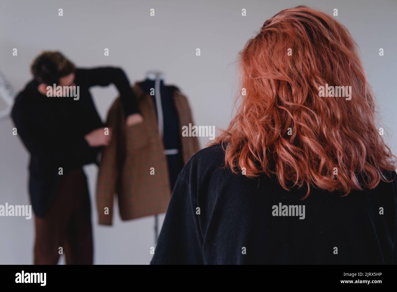 Girl observing a clothing designer. Elegantly dressed clothing designer ...