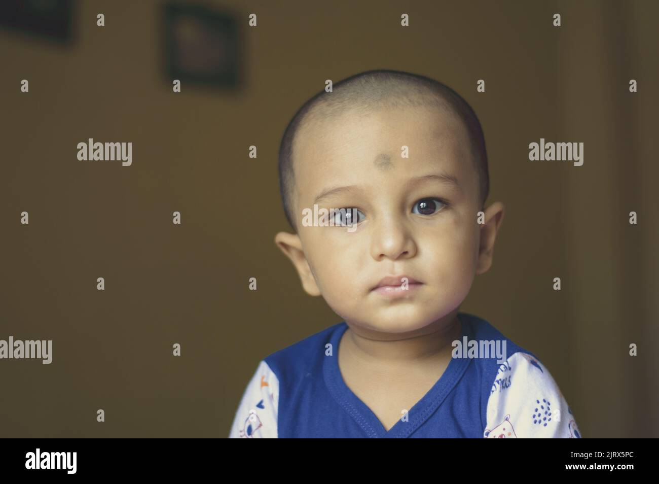 Cute bald indian baby boy in blue and white shirt looking away. Head ...