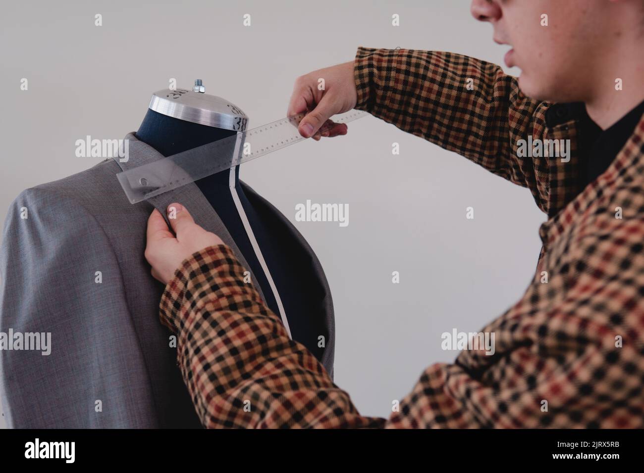 Fashion designer measuring a garment. Caucasian blond man designing ...
