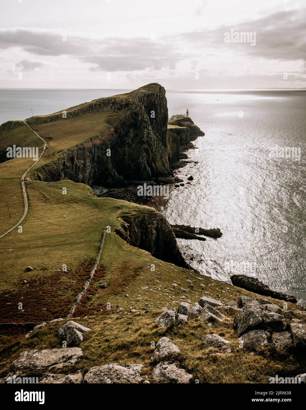 A vertical view of the coastline cliff of the sea under the cloudy sky ...