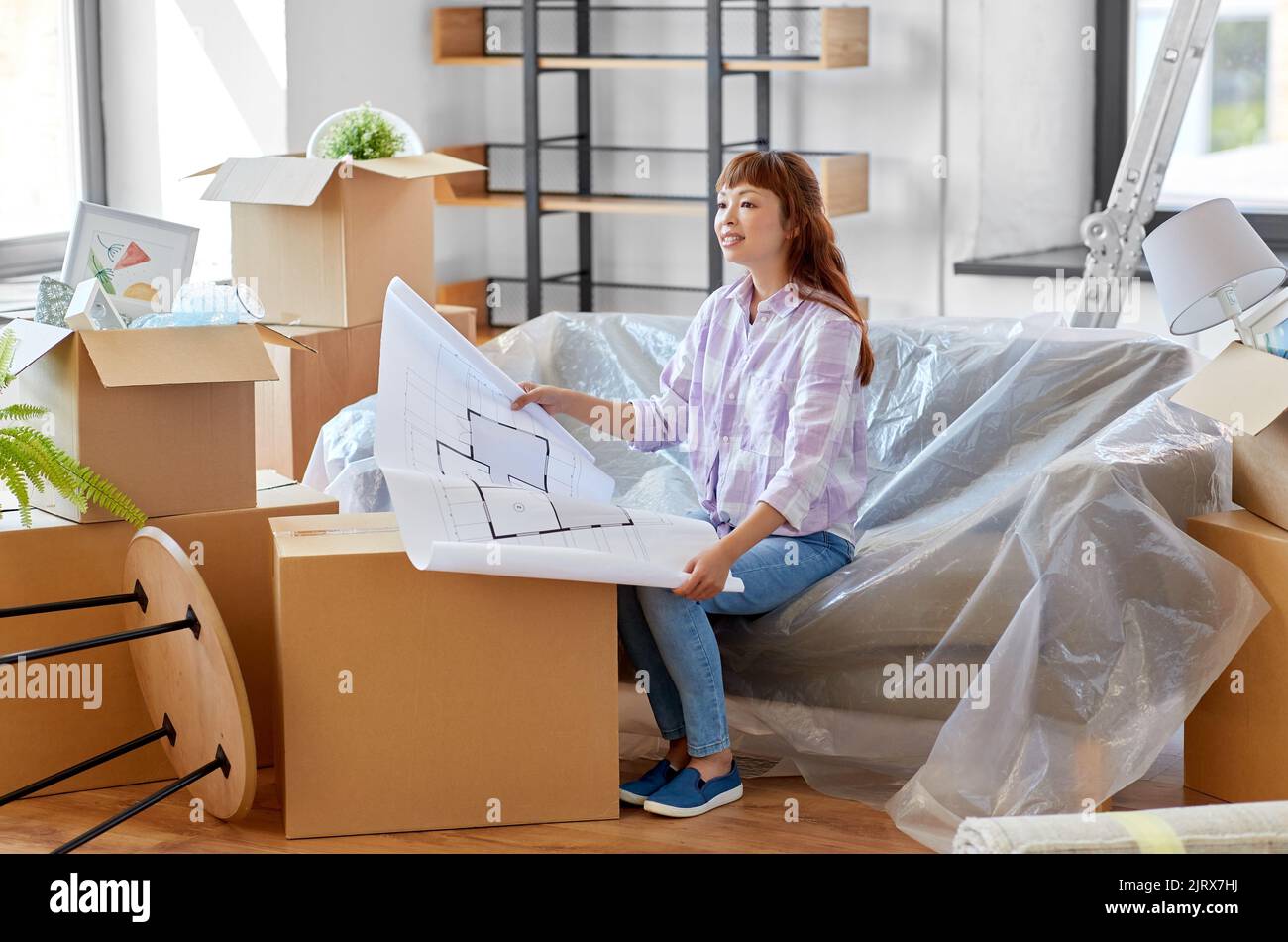 woman with blueprint and boxes moving to new home Stock Photo - Alamy
