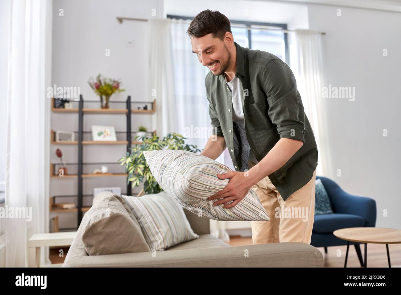 happy smiling man arranging sofa cushions at home Stock Photo - Alamy