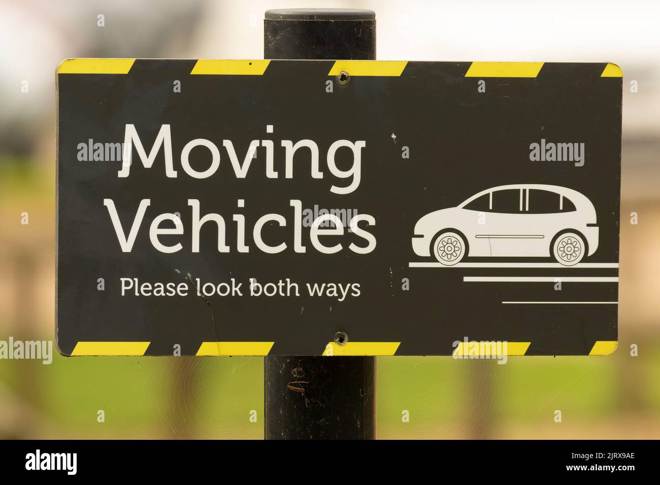 A pedestrian crossing warning sign saying "Moving Vehicles, please look ...