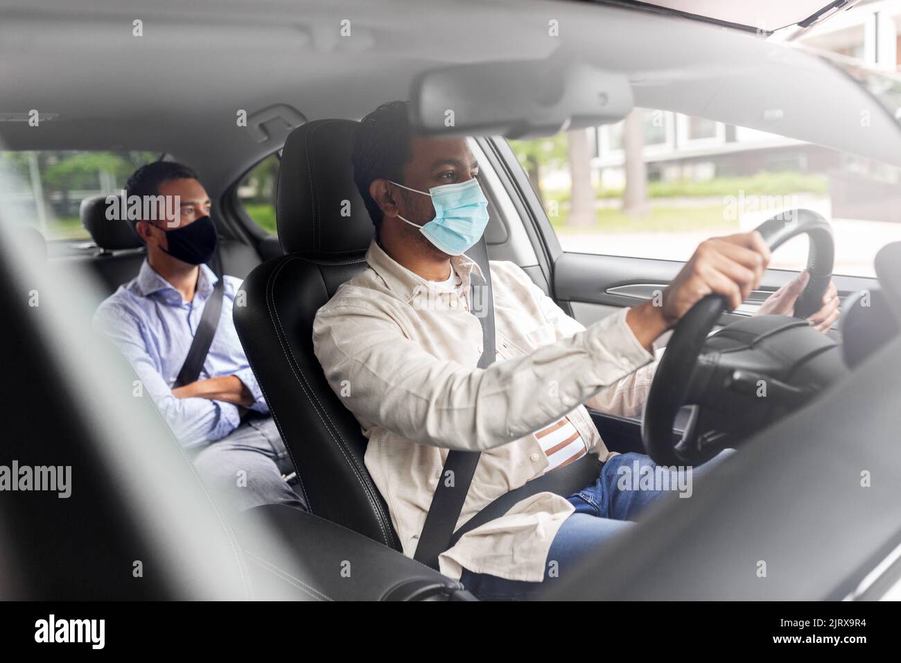 male driver in mask driving car with passenger Stock Photo - Alamy