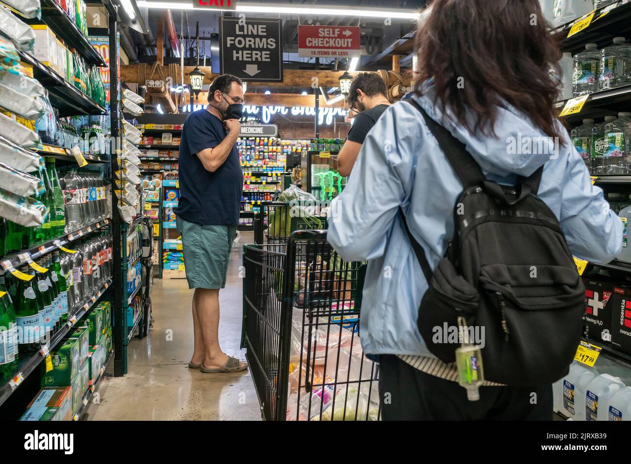 Consumers wait at a check-out line after shopping in a supermarket in ...
