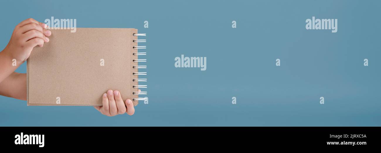 Notepad in hand. Blank notepad in the hands of a child on a blue ...