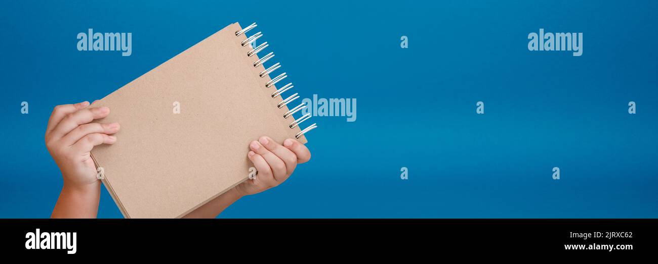Notepad in hand. Blank notepad in the hands of a child on a blue ...