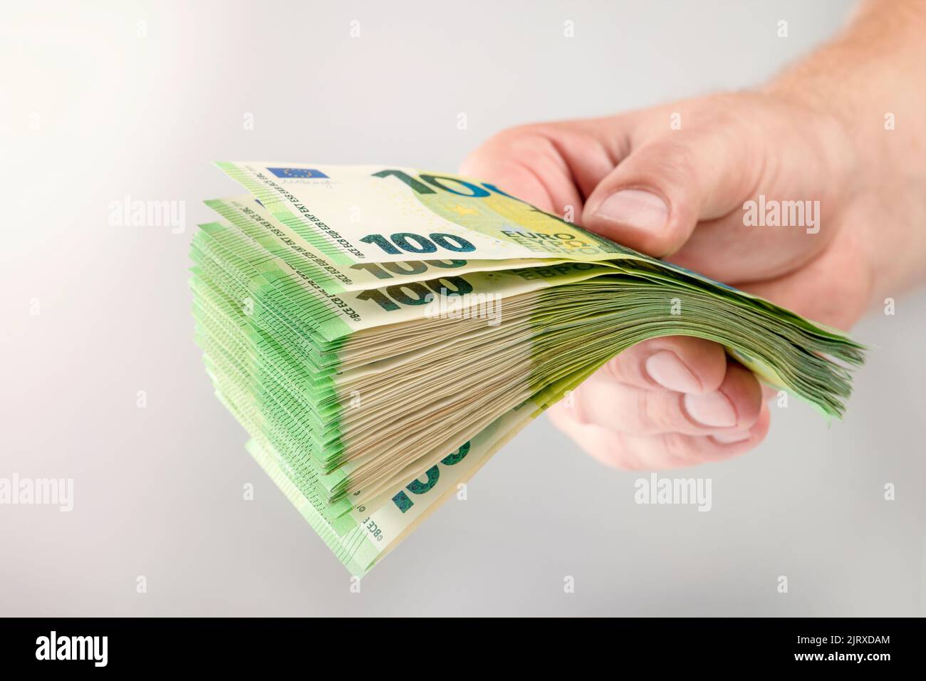 Large stack of euros in hand. Banknotes of 100 euros in a male hand on ...