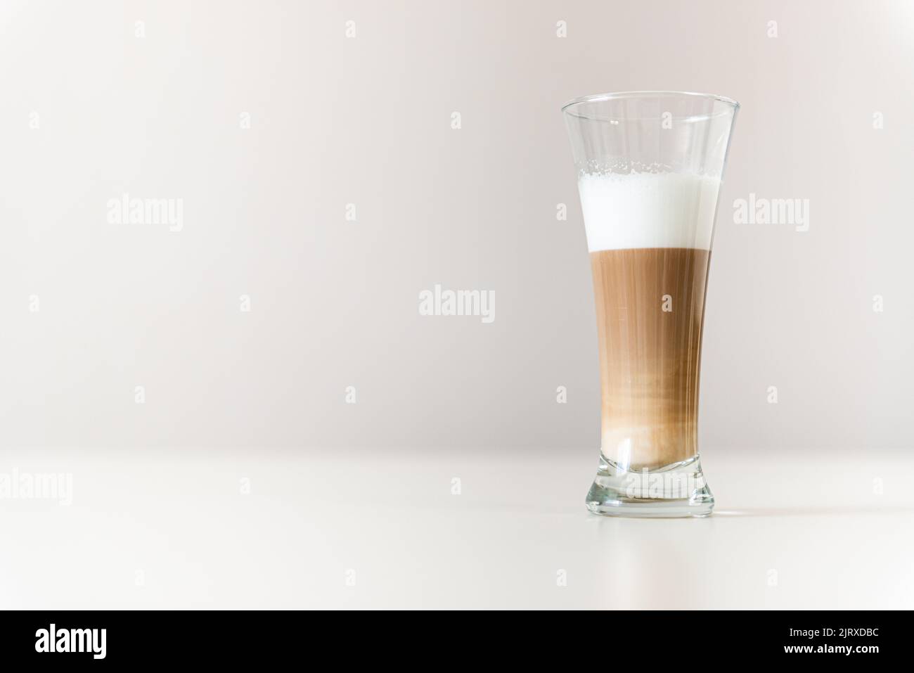 multi-layered coffee in a transparent glass on a gray background and a ...