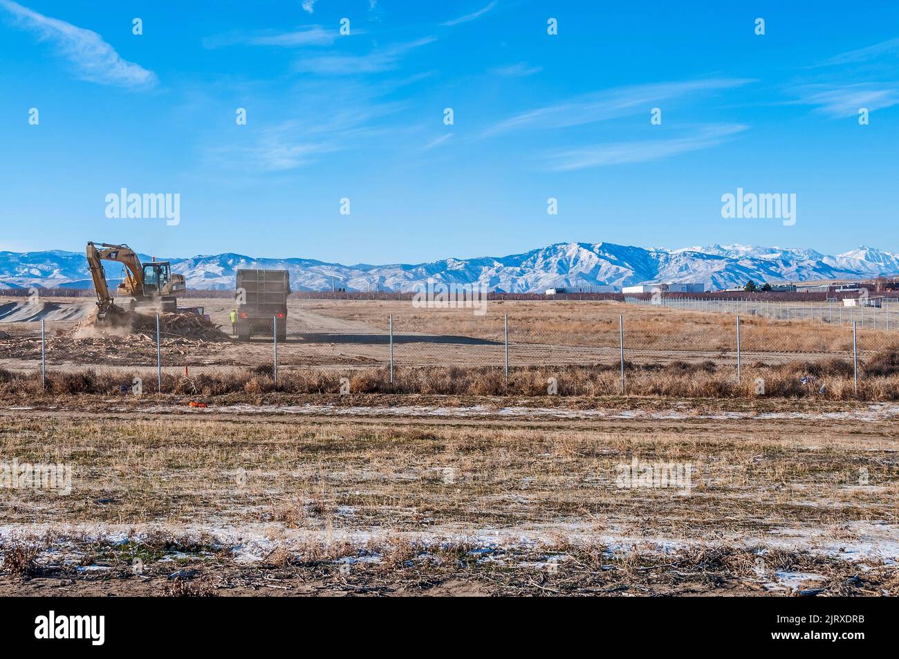 A power shovel loads solid waste into a large truck container for ...