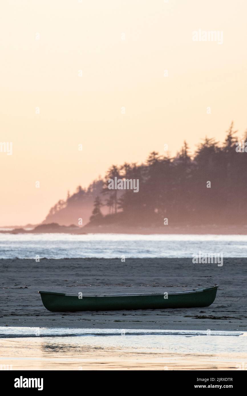 A vertical shot of a canoe on a sandy beach with a background of sea ...
