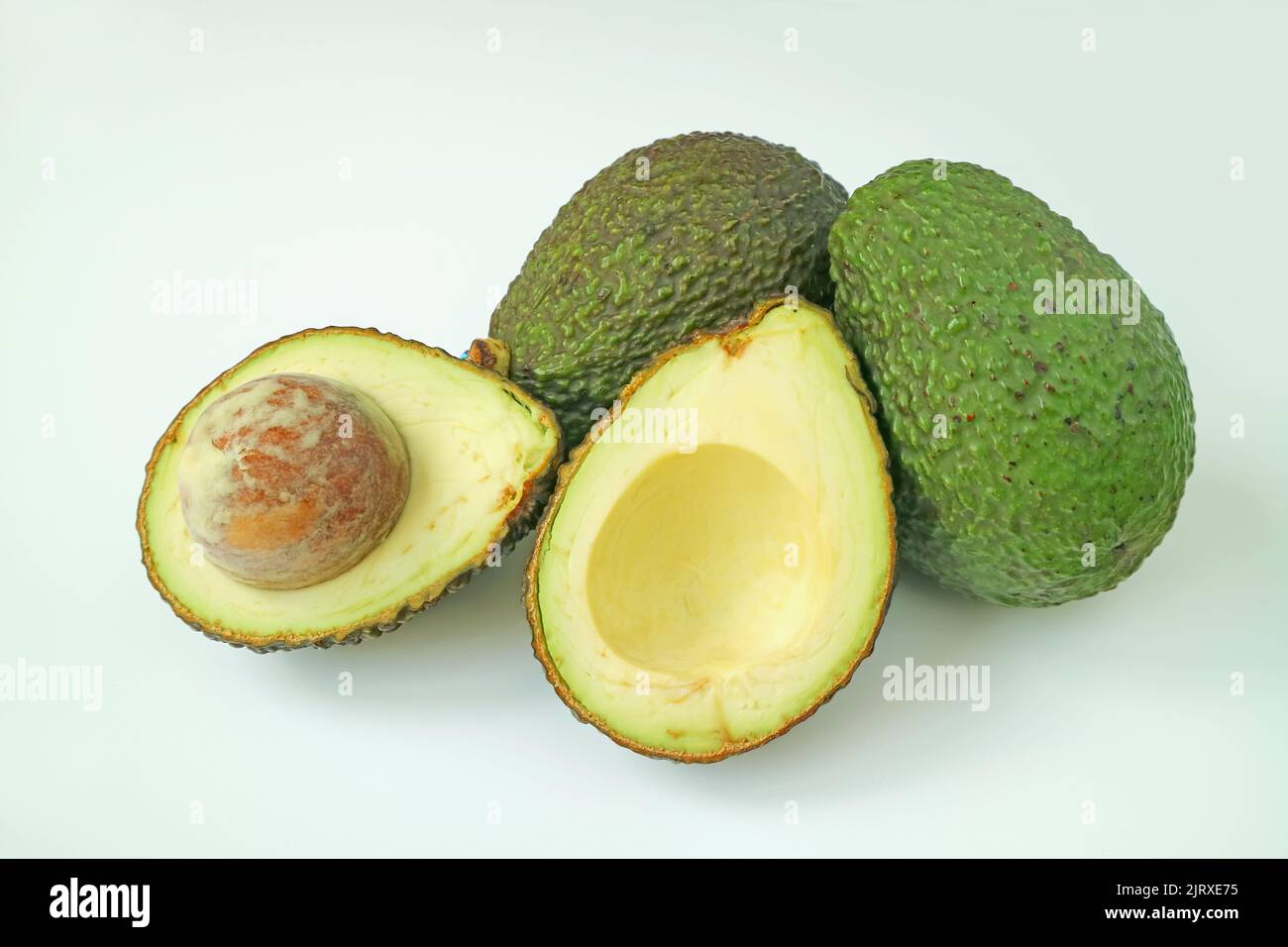 Cut in half fresh ripe avocado with whole fruits isolated on white ...