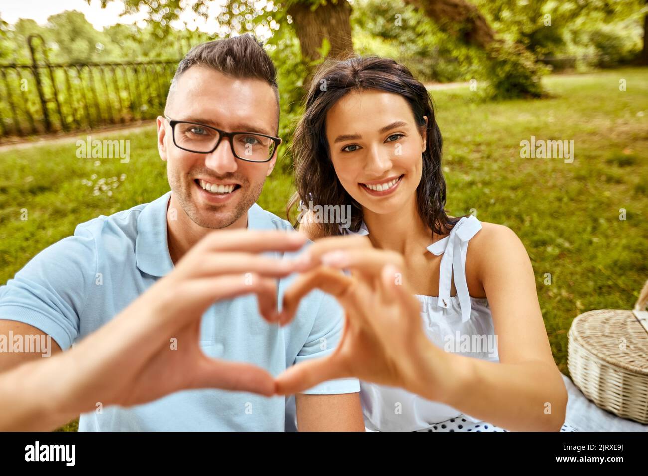 happy couple making finger heart at summer park Stock Photo - Alamy