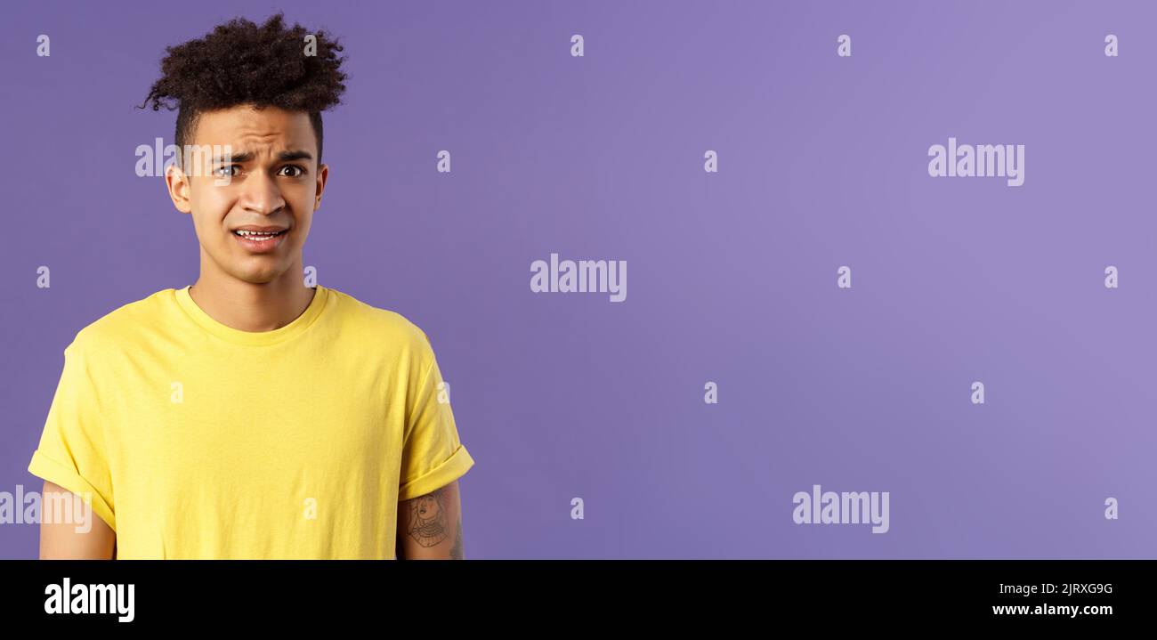 Close-up portrait of awkward and embarrassed young hispanic guy looking ...