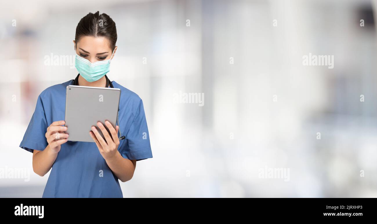 Young nurse using a mobile tablet app. Wide background with large copy ...