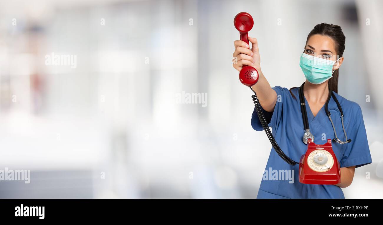 Young nurse making a phone call, with a vintage telephone covid and ...