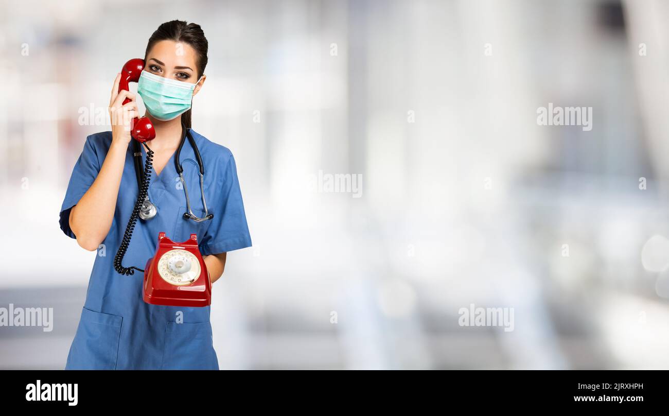 Nurse making a phone call, with a vintage telephone covid and ...