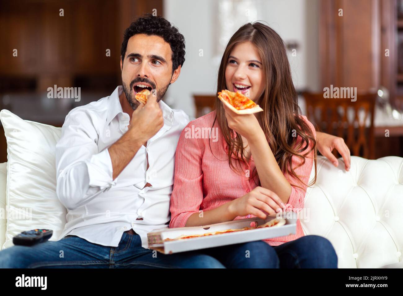 Couple eating pizza and watching TV Stock Photo - Alamy