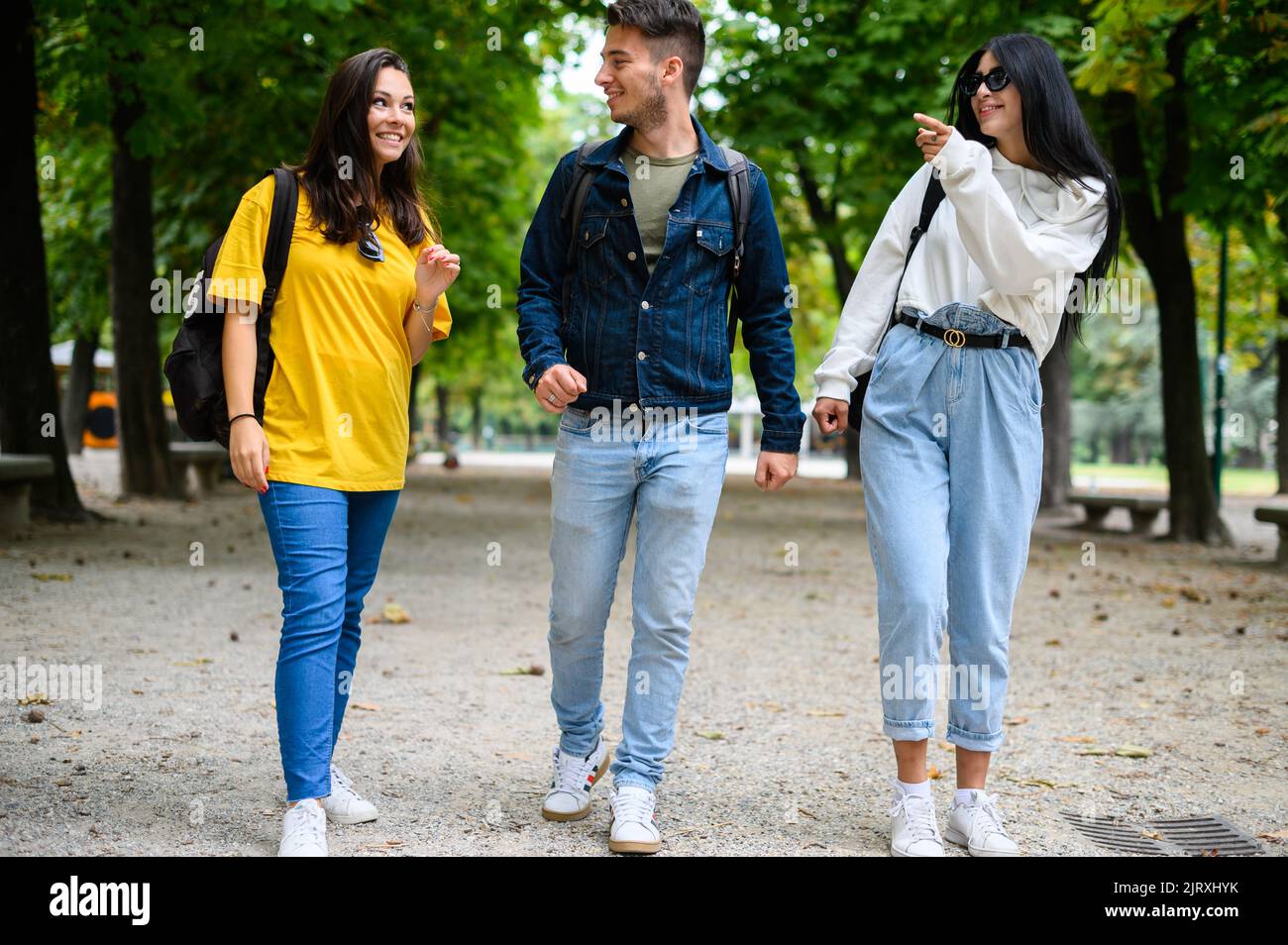 Happy students outdoor walking and talking to each other, full length ...