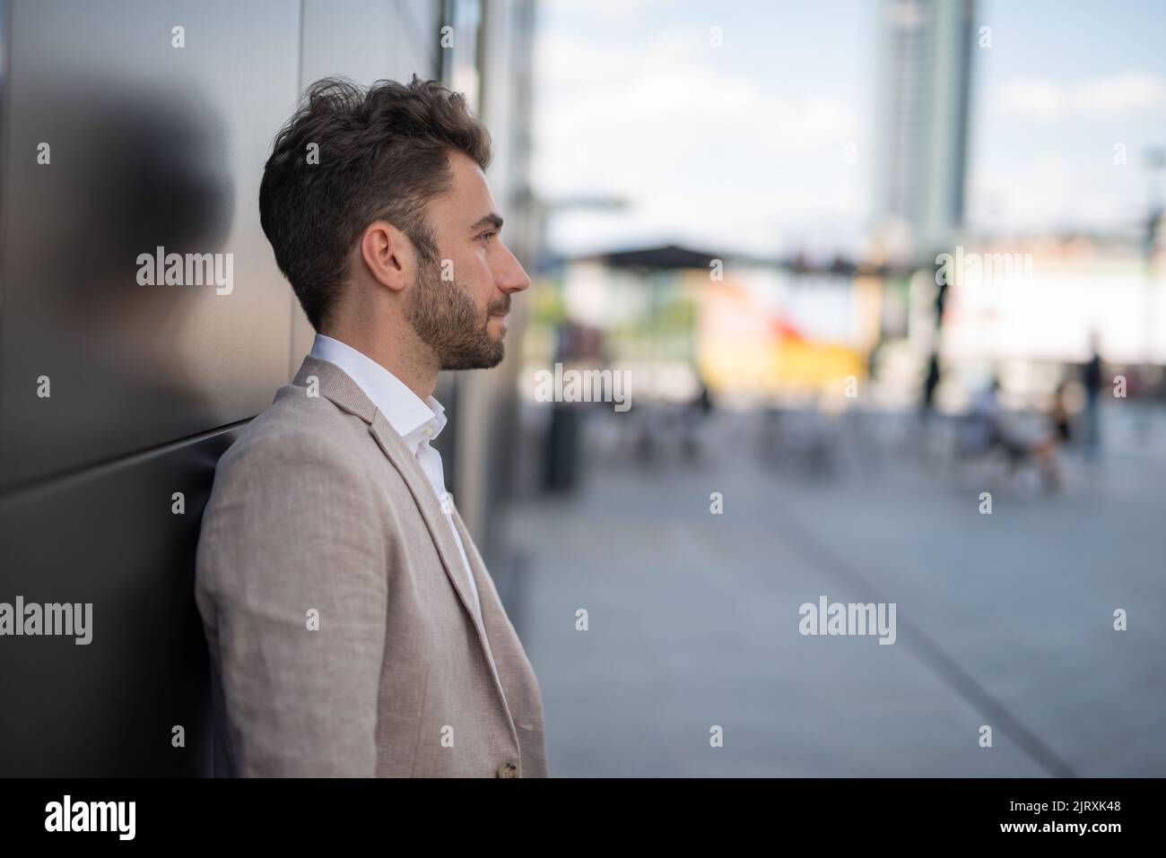 Businessman leaning against a wall in a city plaza Stock Photo - Alamy