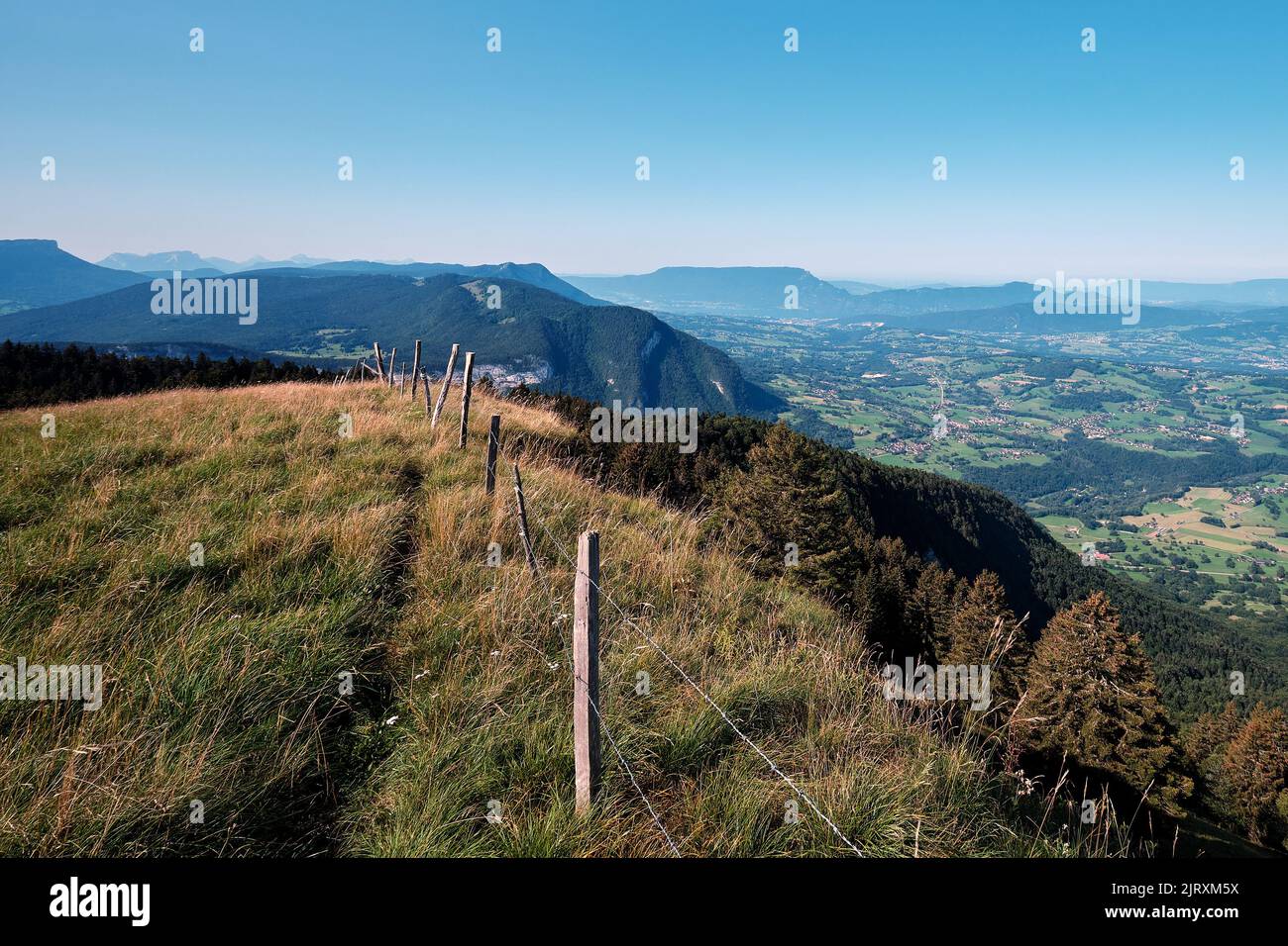 The fences on top of a hill with mountains covered with trees and grass ...