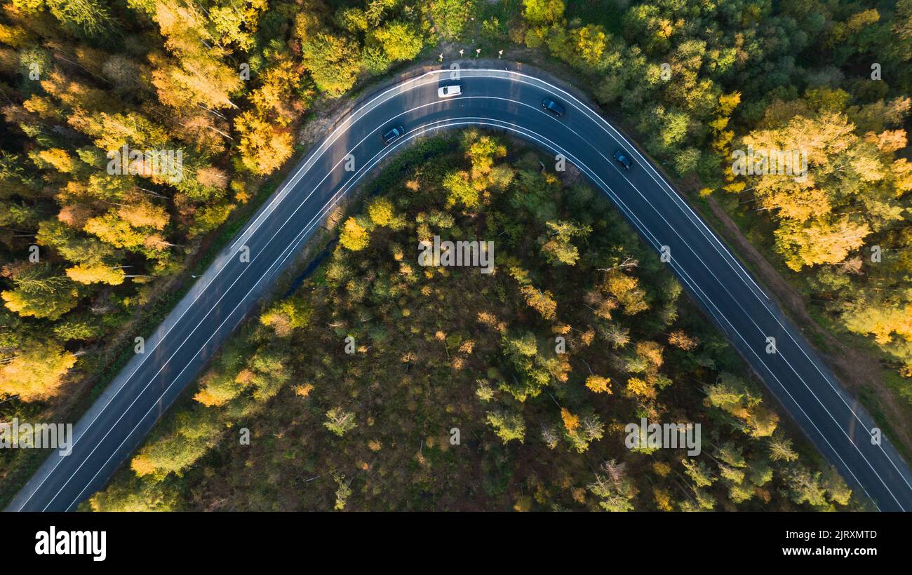 Aerial view of a bend in the road with cars in the middle of yellow ...