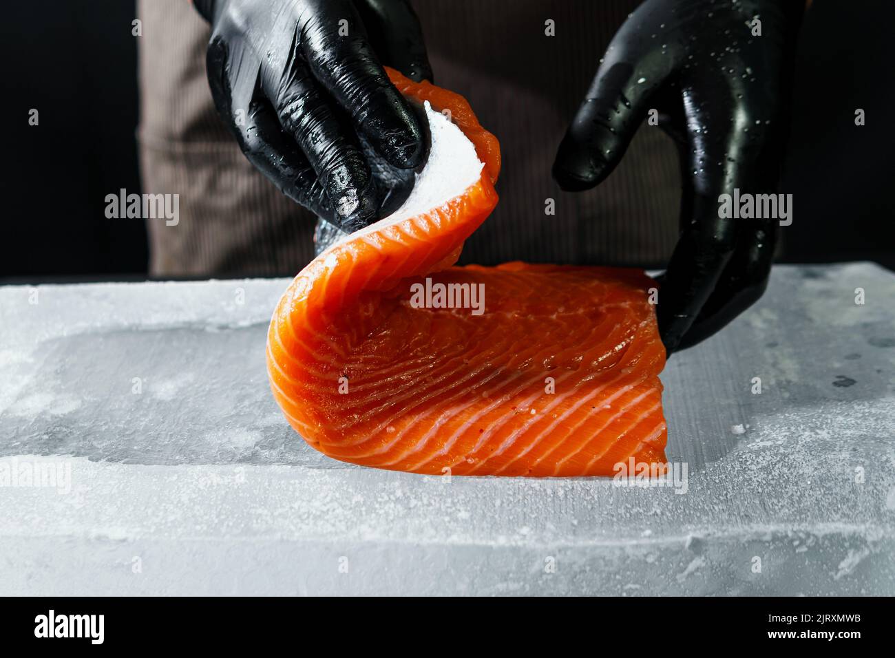 Close-up of chef hand prepared to cooking fresh salmon fillet, black ...
