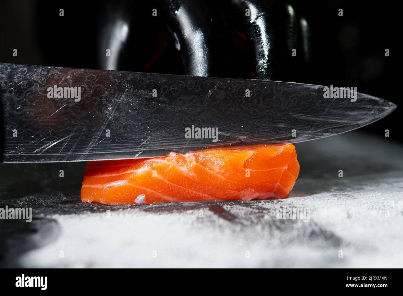 Close-up of chef hand prepared to cooking fresh salmon fillet, black ...