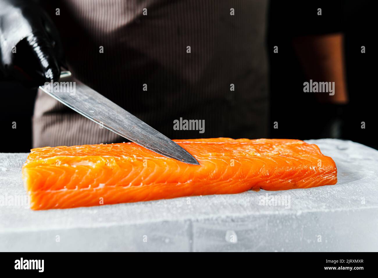 Close-up of chef hand prepared to cooking fresh salmon fillet, black ...