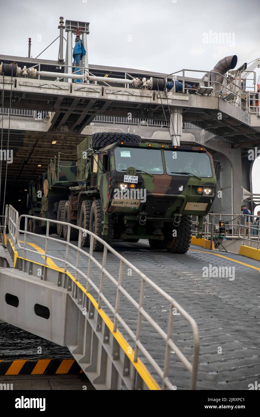 A military vehicle drives down the ramp of the high-speed transport ...