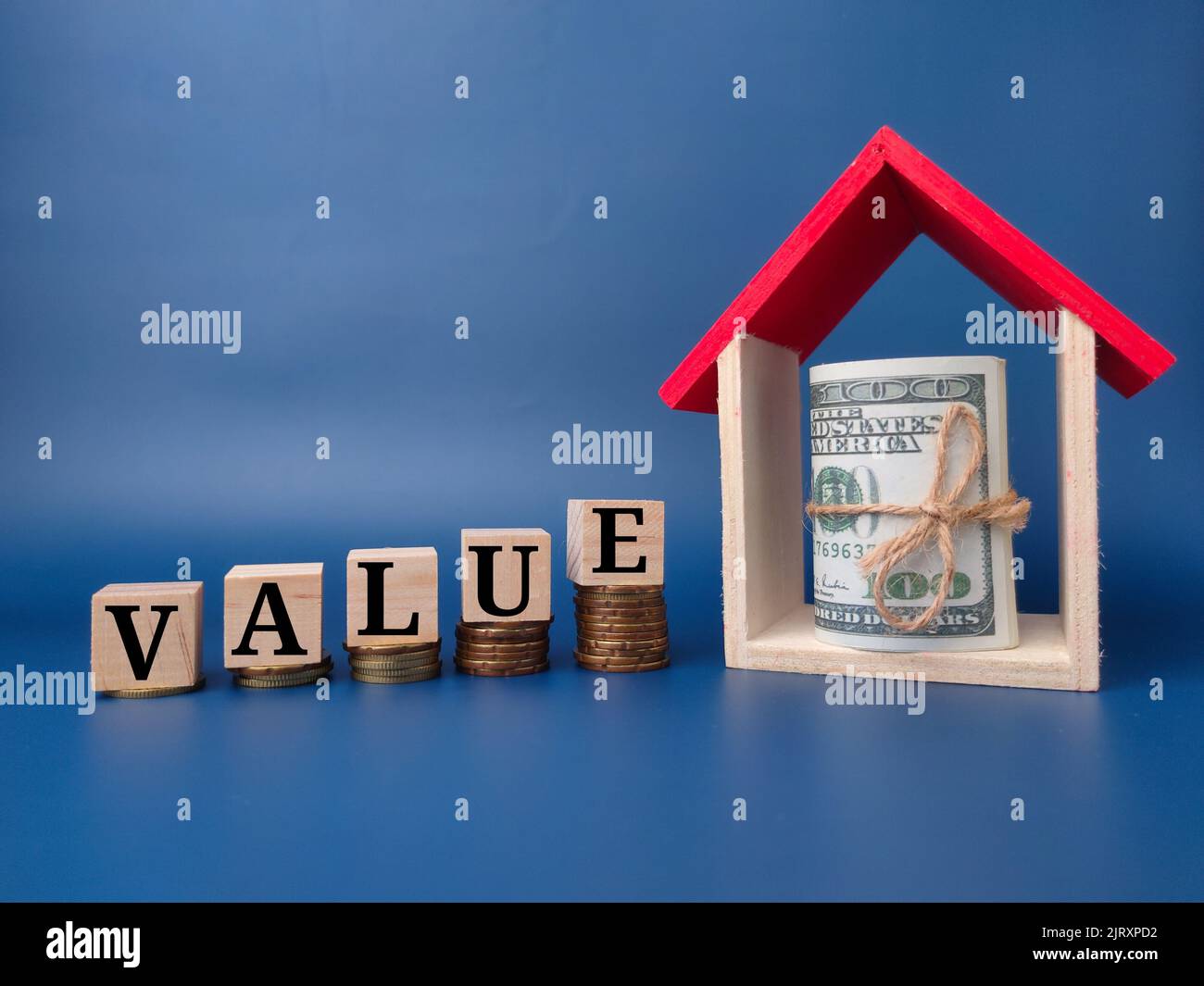 A toy house and banknote with the word VALUE on a blue background- real ...