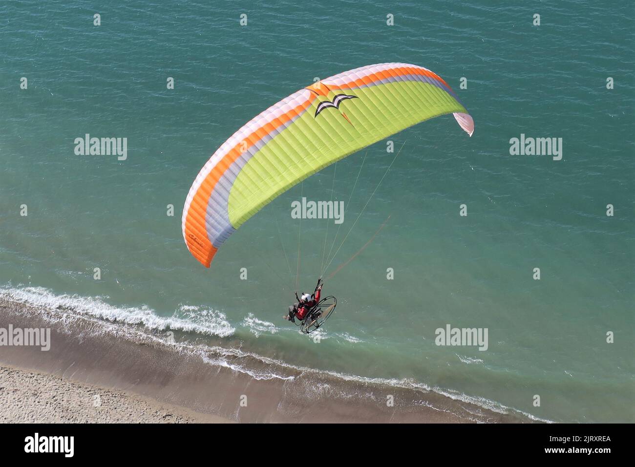paragliding pilot flying in smooth air on colorfum paraglider wings in ...