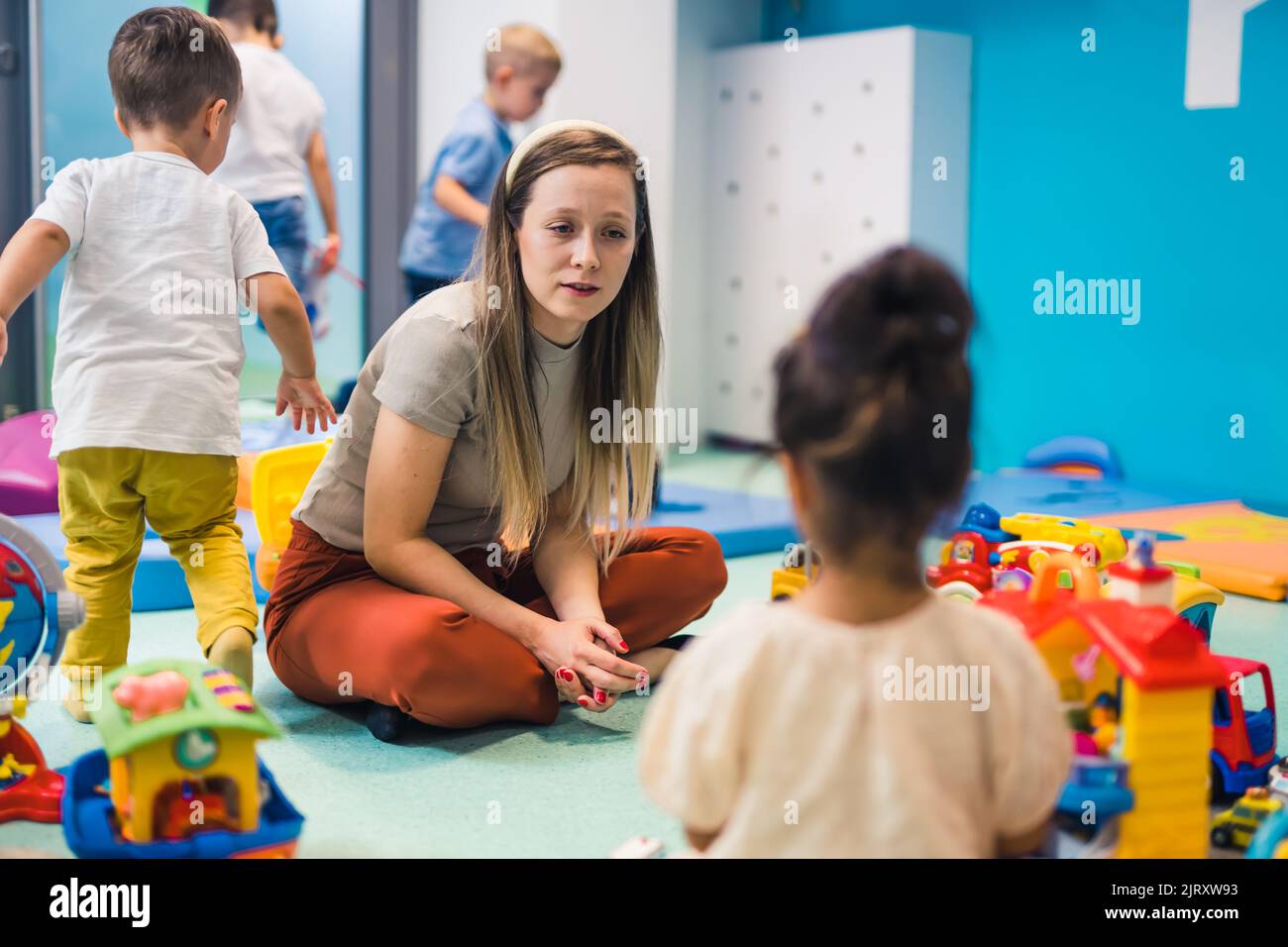 Nursery school. Toddlers and their tutor playing with colorful plastic ...