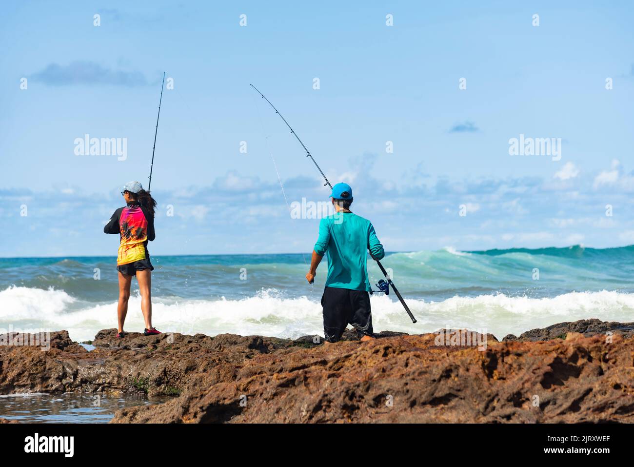Man and woman fishermen on top of rocks with fishing rod. City of ...