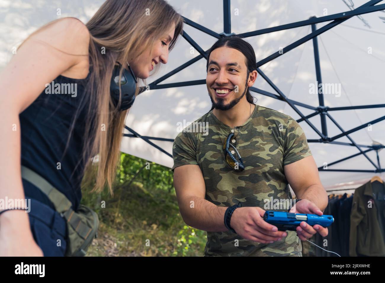 Caucasian dark-haired male gun reseller in a moro t-shirt showing a ...