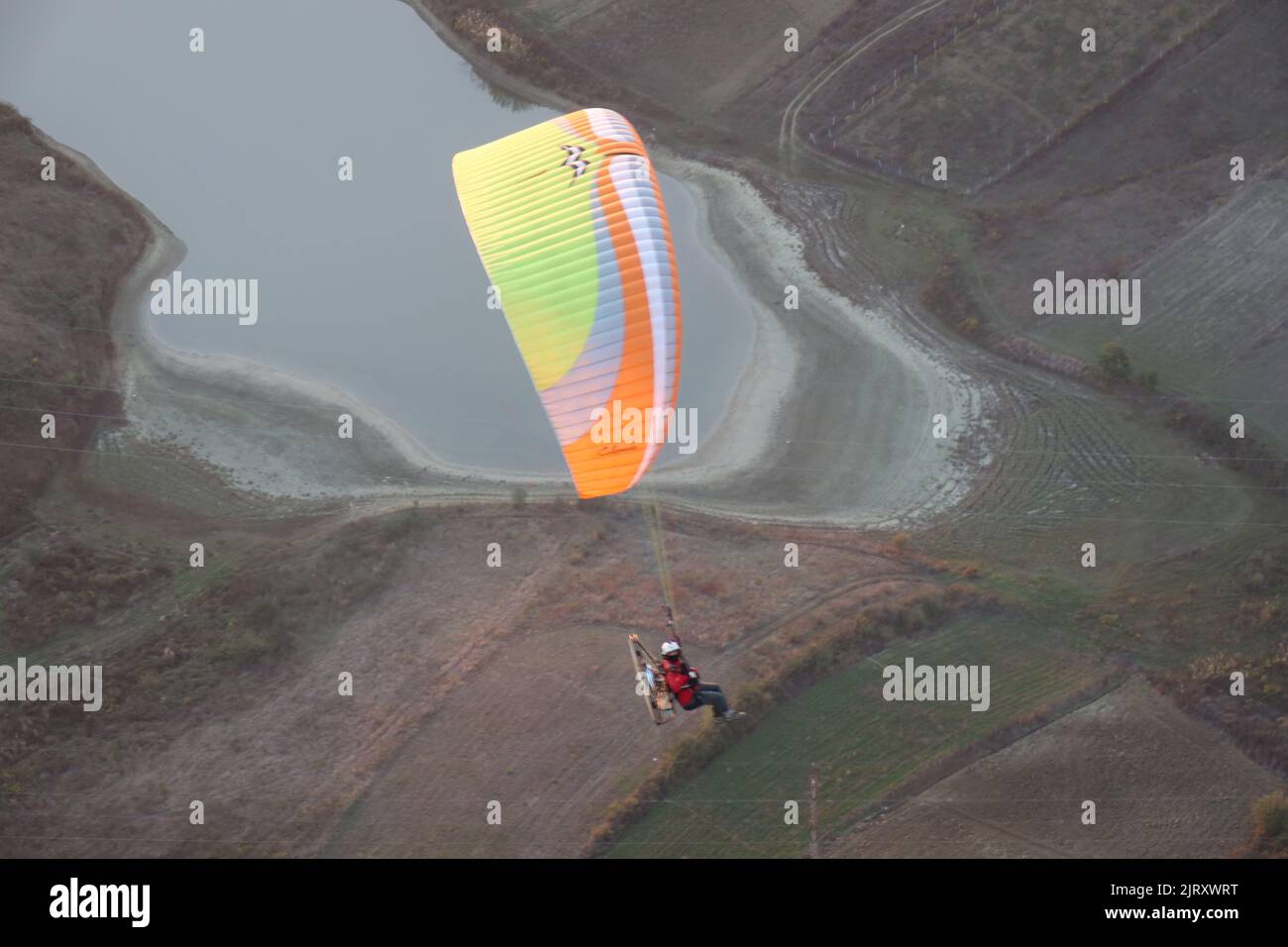 paragliding pilot flying in smooth air on colorfum paraglider wings in ...