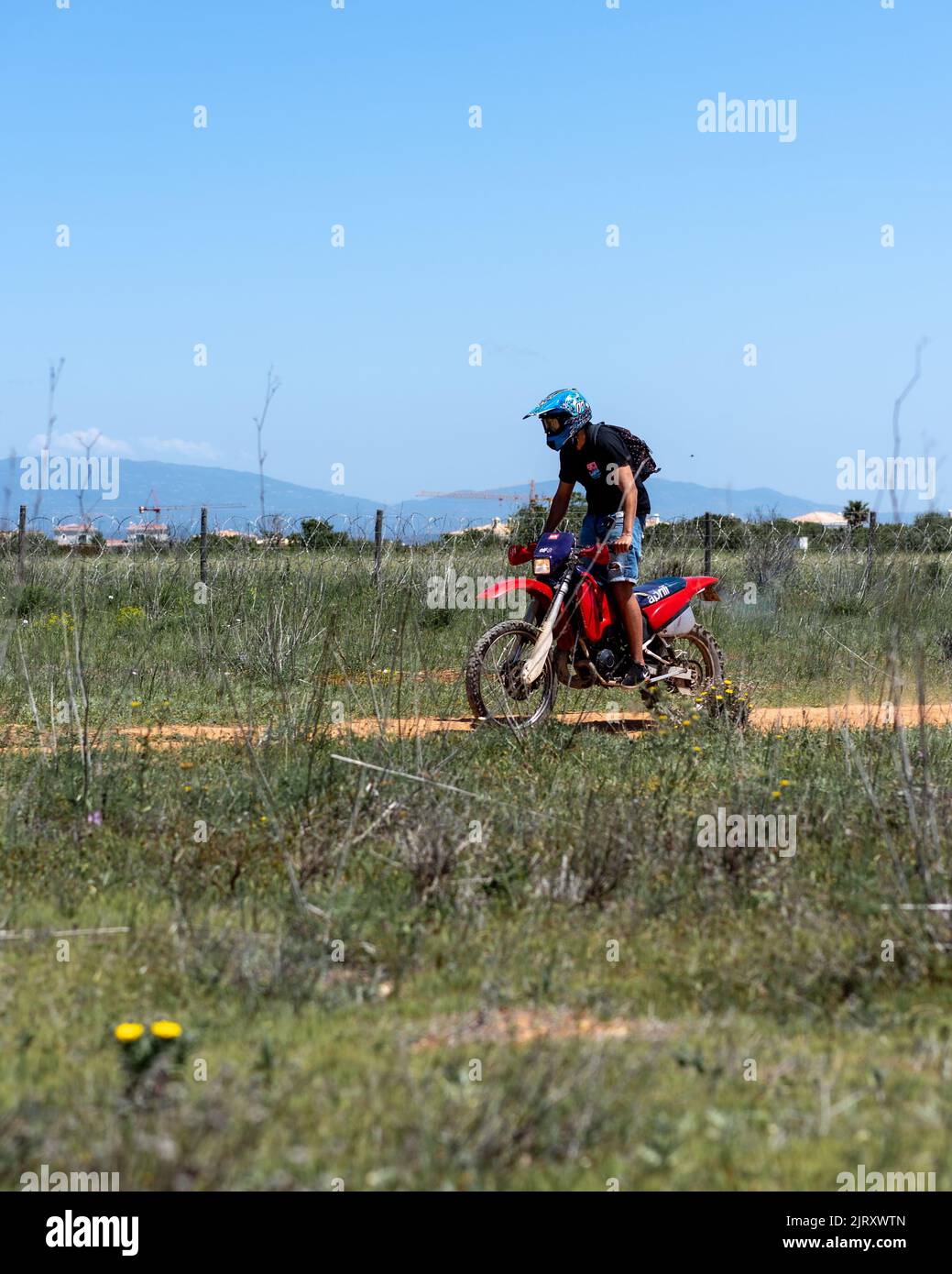Motocross rider standing on a motorbike while riding on a trail with ...