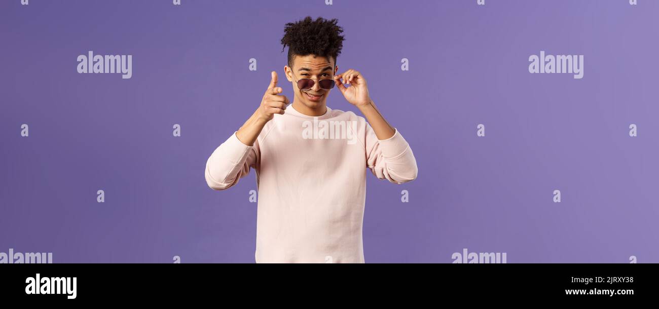 Portrait of cheeky handsome young man wearing sunglasses, take them off ...