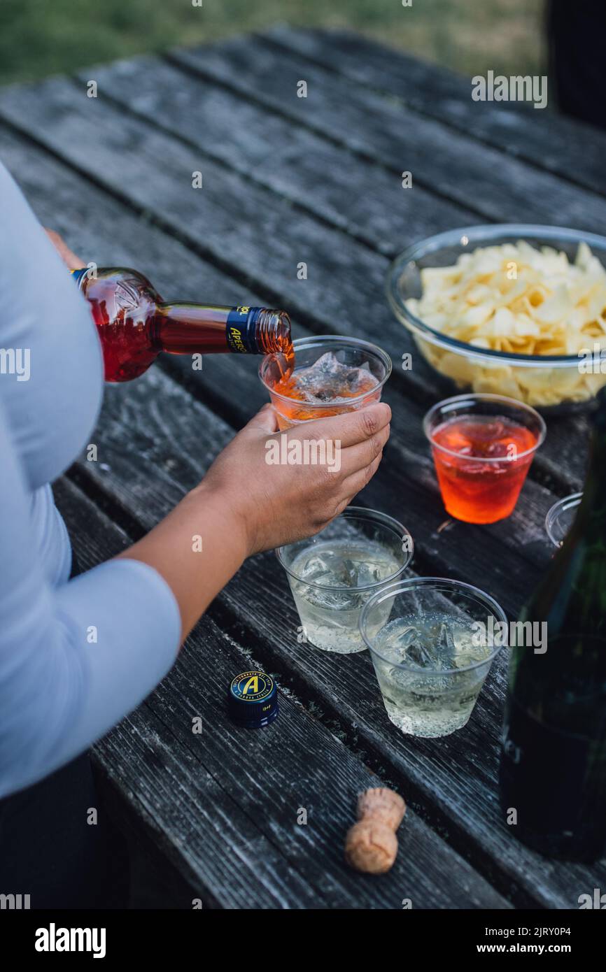 woman pouring Aperol, making Spritz aperitif cocktails outdoors on ...