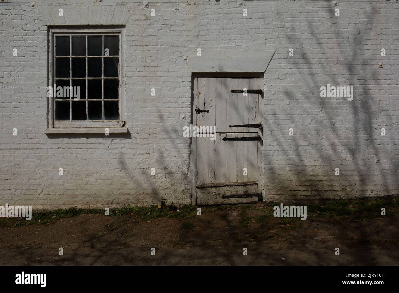 The weathered white stable door with a vintage paned window of an old ...