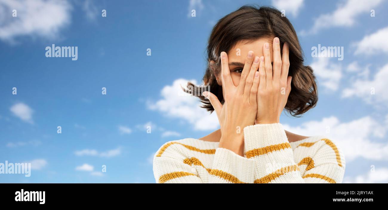 young woman looking by one eye through her fingers Stock Photo - Alamy