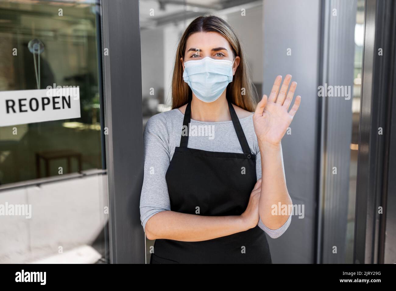 woman in mask with reopen banner on door glass Stock Photo - Alamy