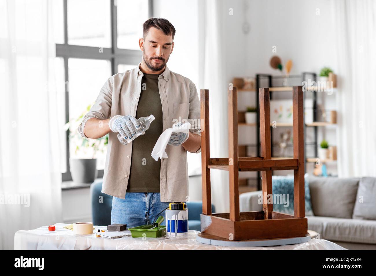 man applying solvent to rag for cleaning old table Stock Photo - Alamy