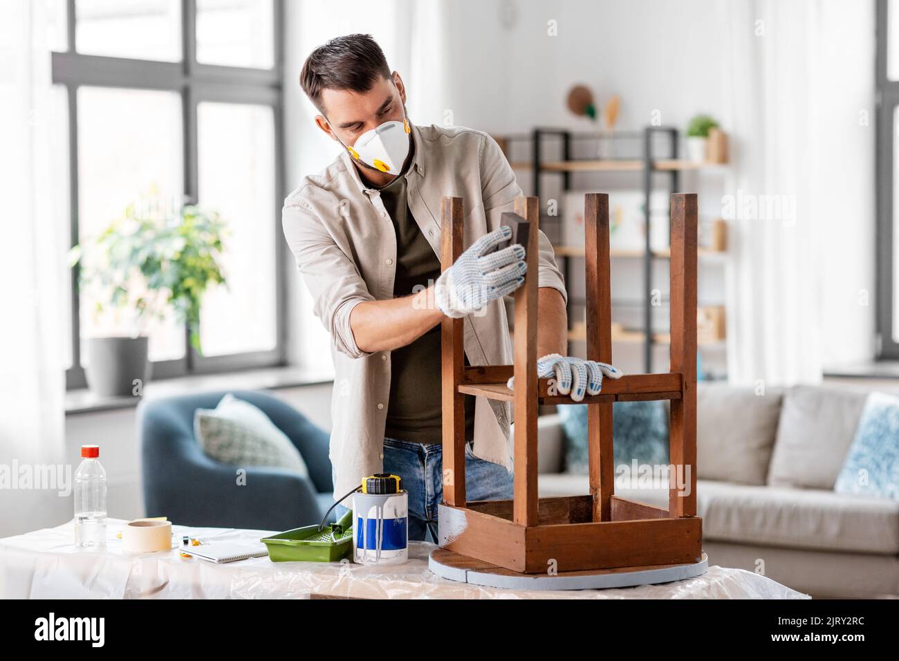 man in respirator sanding old table with sponge Stock Photo - Alamy