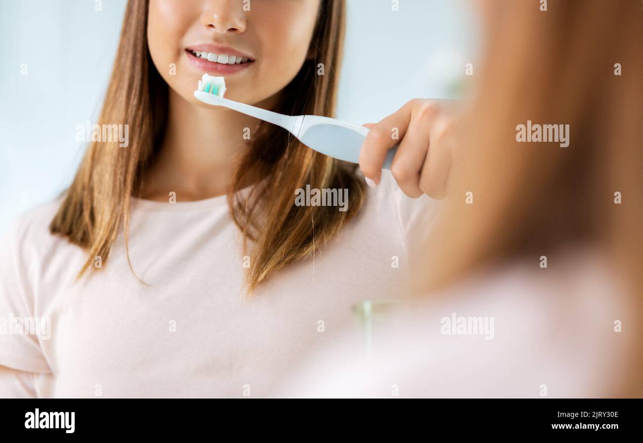 teen girl with electric toothbrush brushing teeth Stock Photo - Alamy